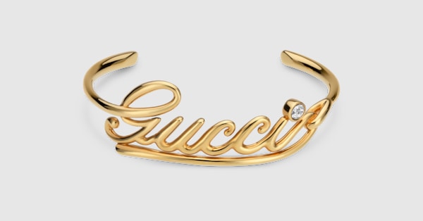 Cuff bracelet with Gucci script in yellow gold toned metal GUCCI US